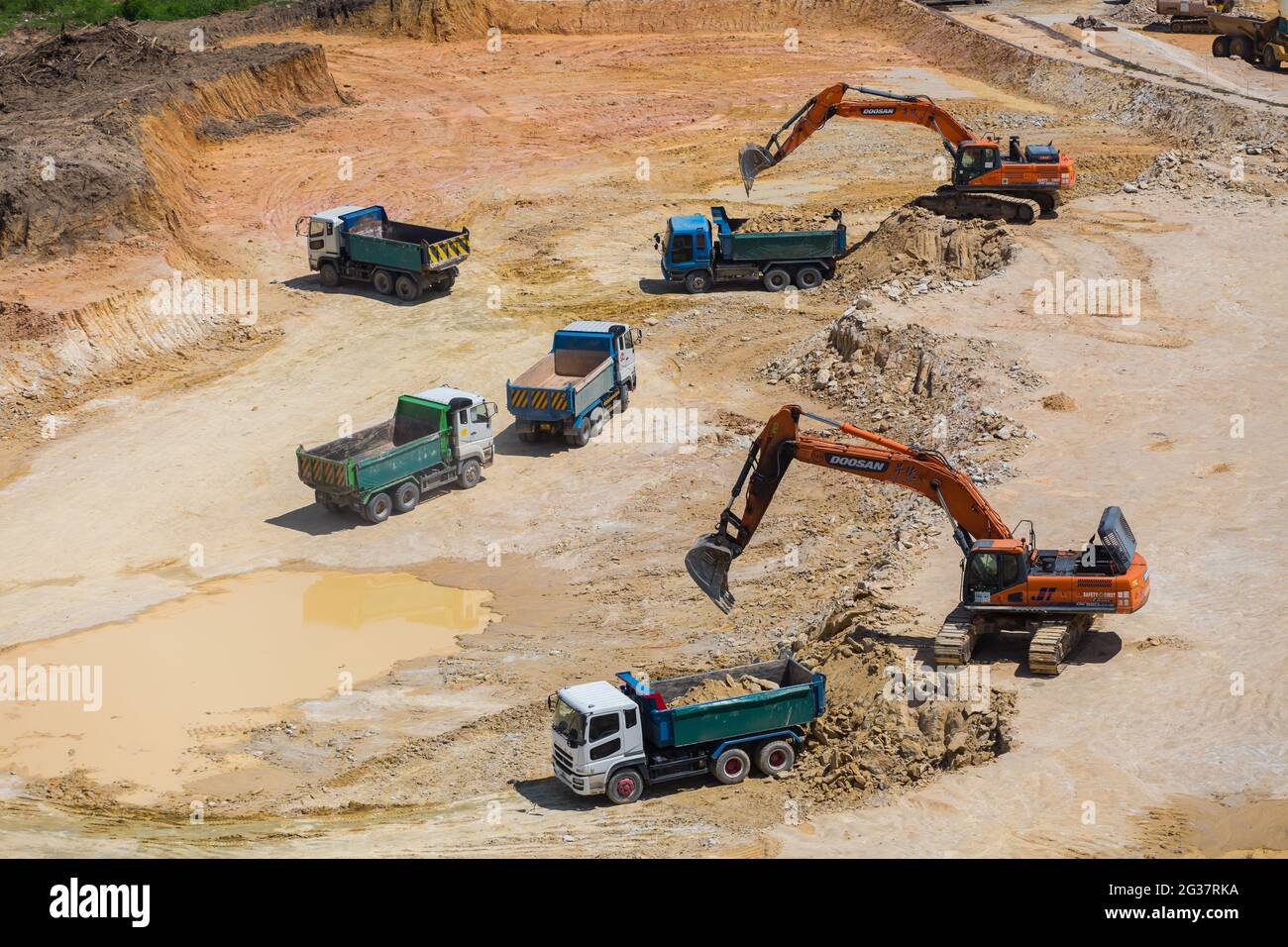 Excavator machines are in sync when digging up the soil and put it on ...