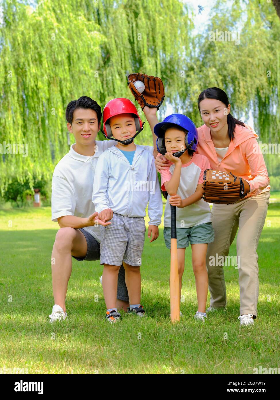 Happy family of four playing baseball in the park high quality photo ...