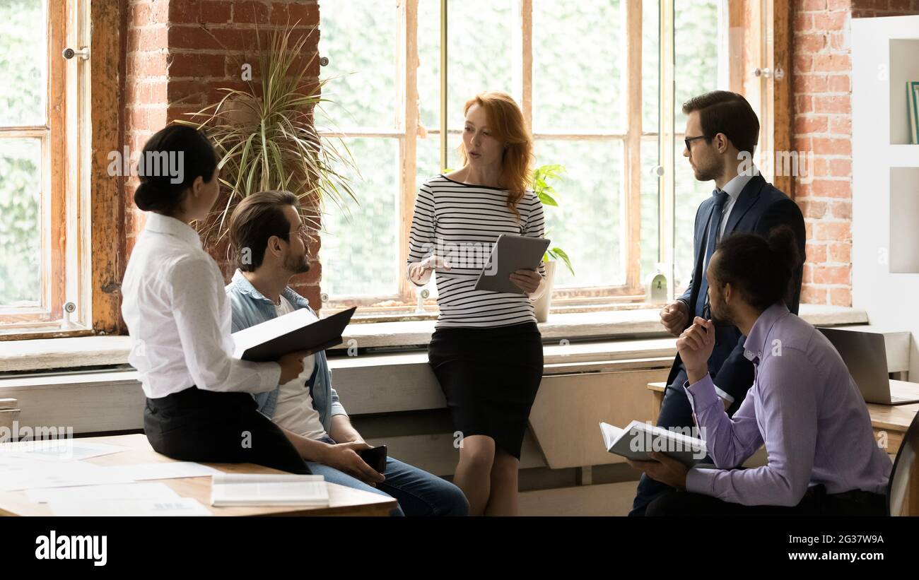 Professional female team leader presenting business ideas to colleagues ...