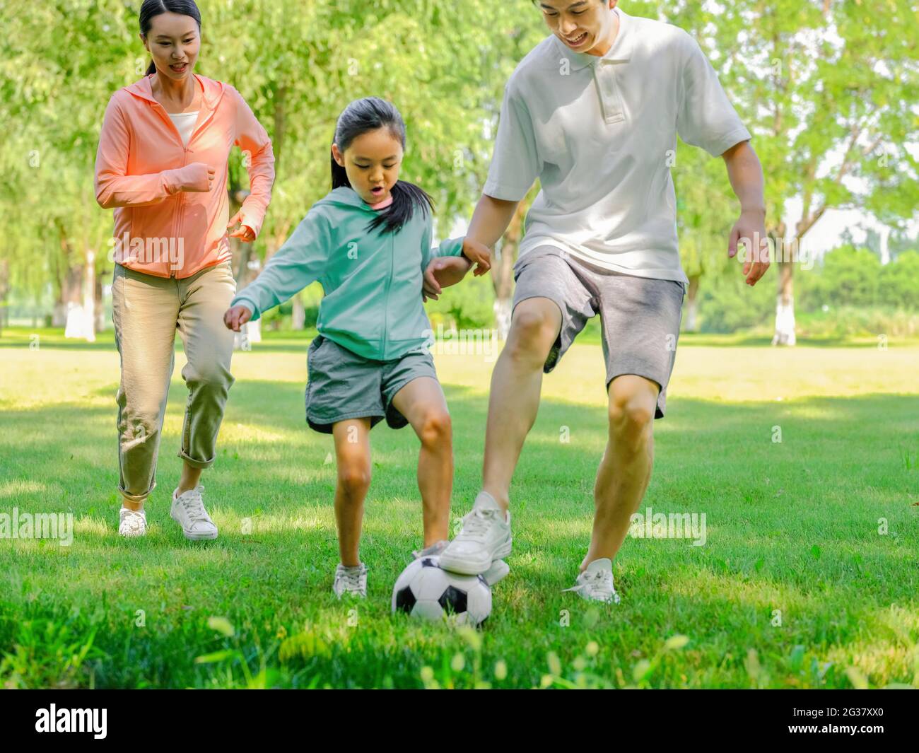 Happy family of three playing football in the park high quality photo ...