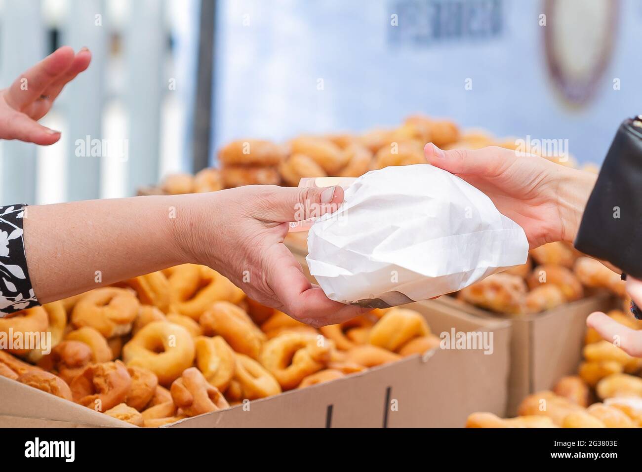 Closeup shot of a female hands selling doughnuts wrapped in paper Stock ...