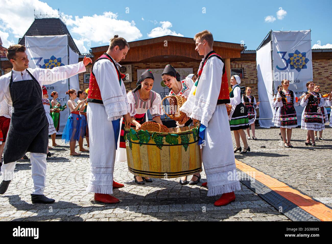 BEREHOVE, UKRAINE - JUNE 13, 2021 - Women fill a wooden tank with ...