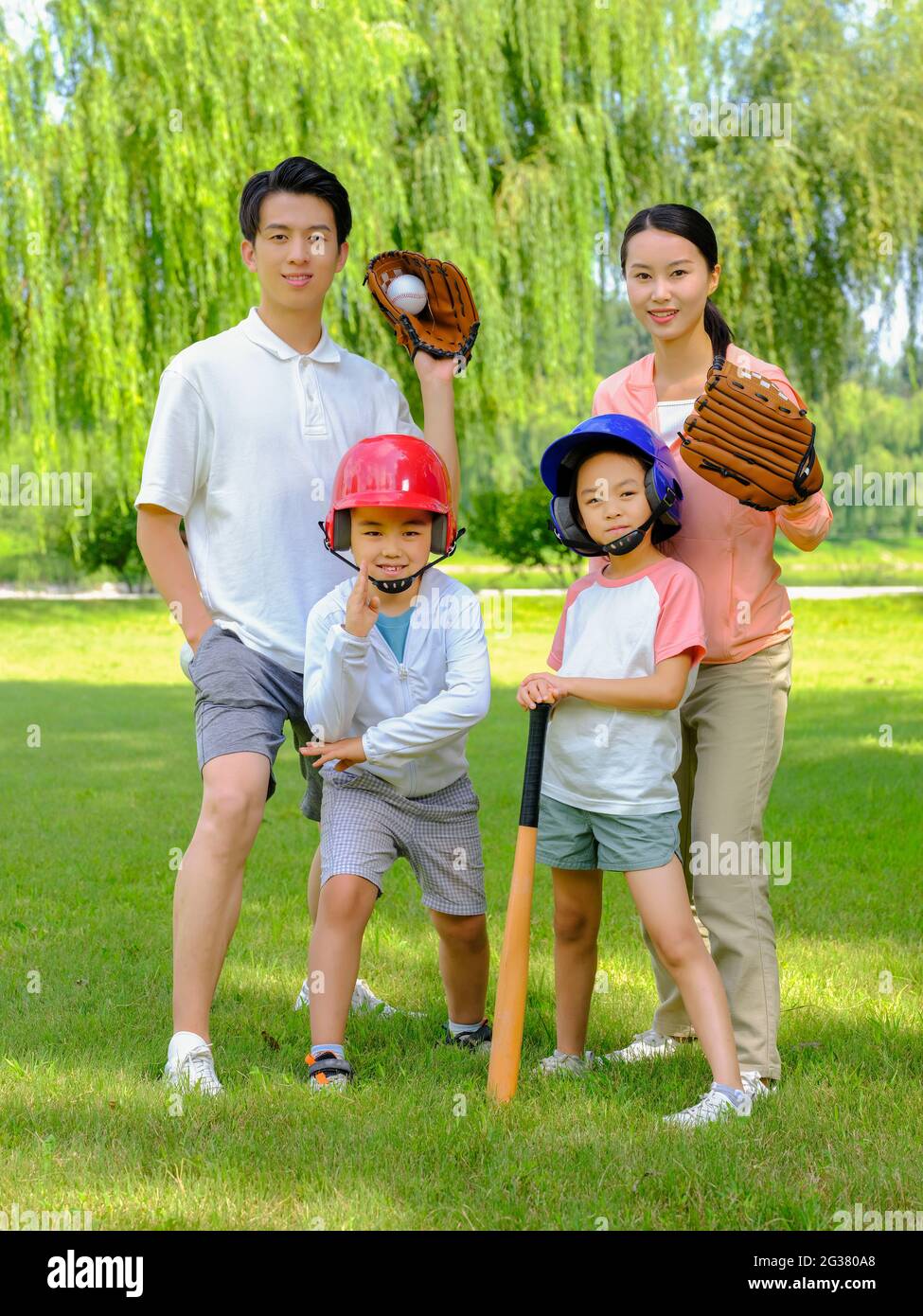 Happy family of four playing baseball in the park high quality photo ...