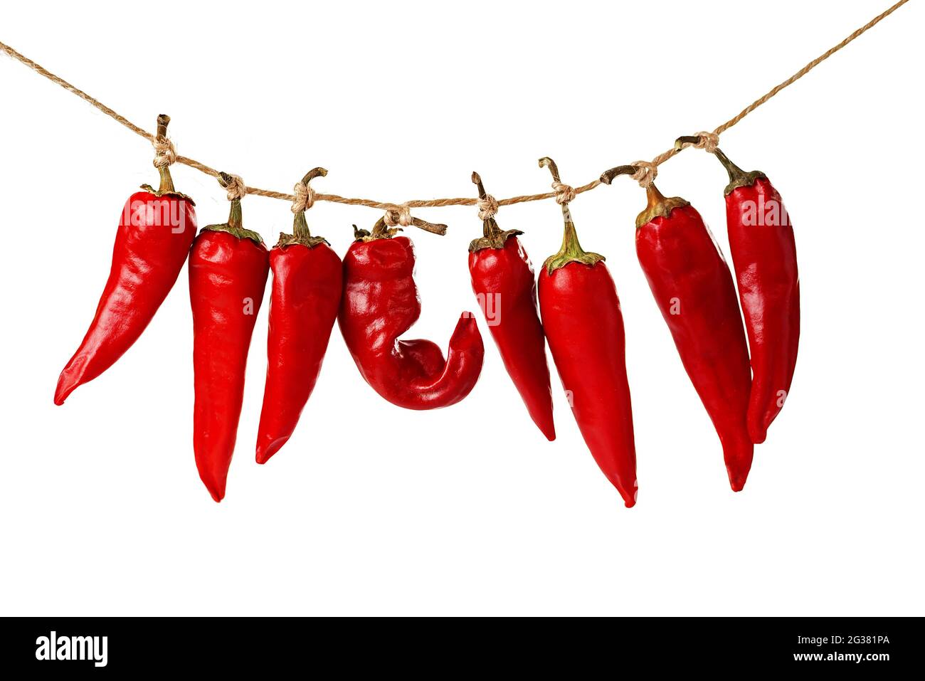 closeup of red chili peppers hanging on a rope isolated on white ...