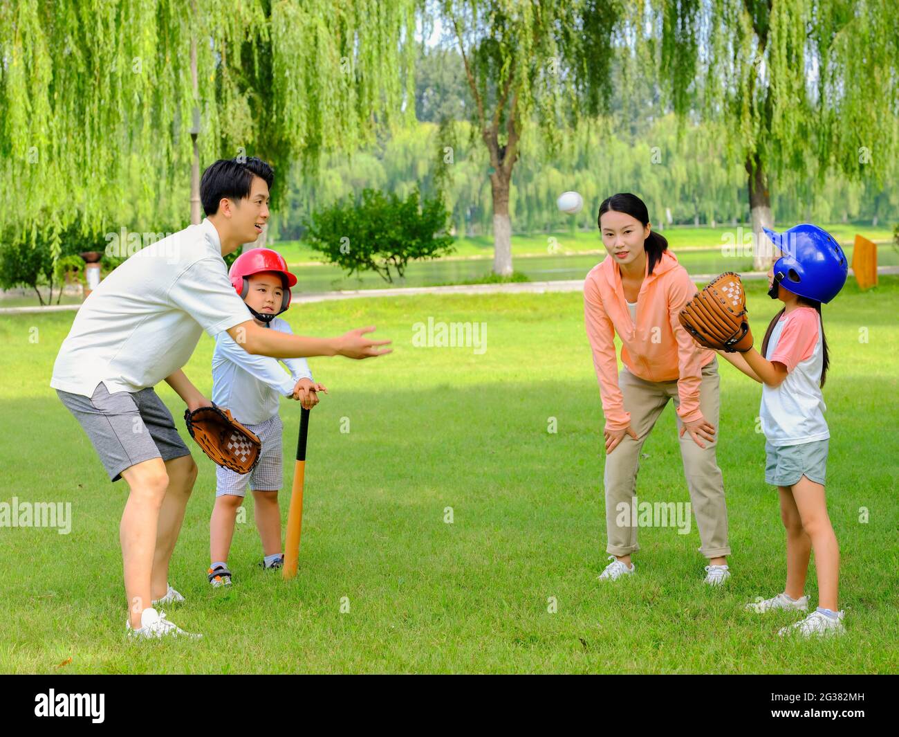Happy family of four playing baseball in the park high quality photo ...