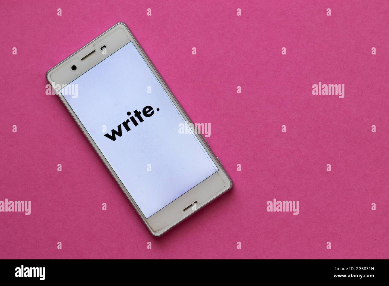 White cell phone on a pink background, the word "write" is written on ...