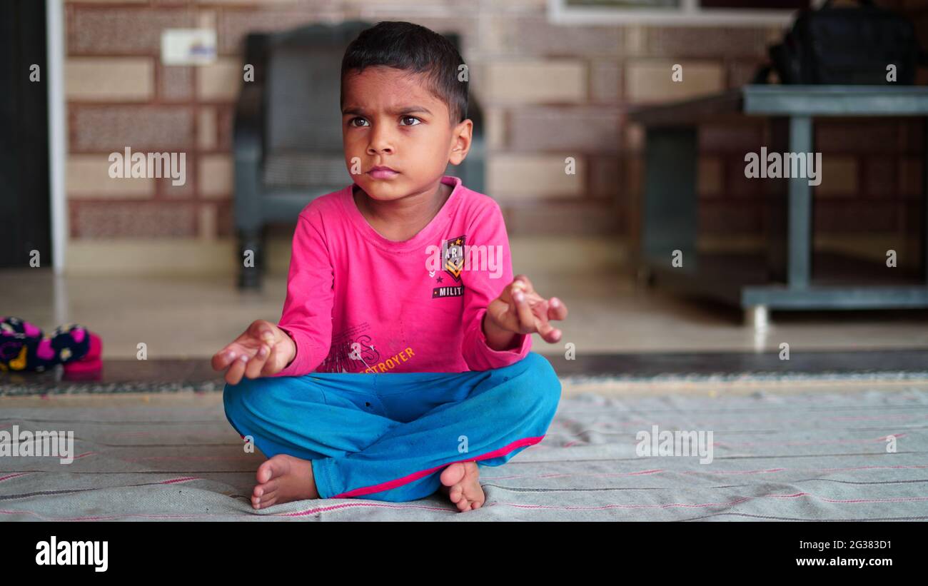 Kids yoga. Little Indian boy doing yoga exercise and watching ...