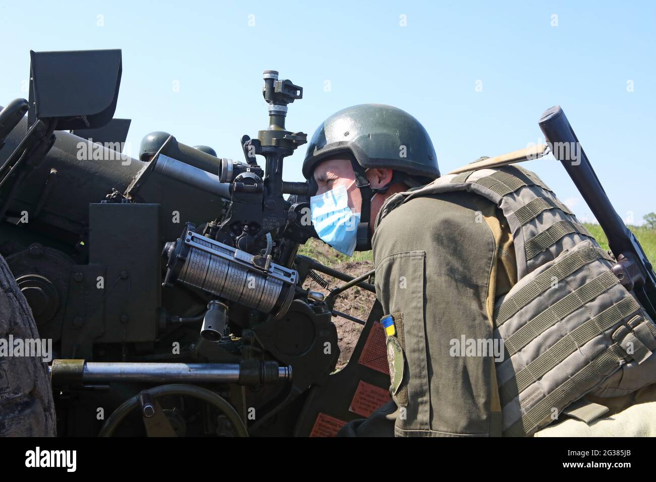 KHARKIV REGION, UKRAINE - JUNE 14, 2021 - A soldier looks through a ...