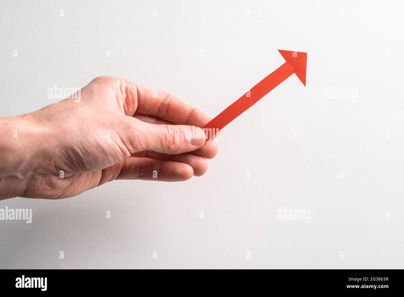 Hand holding a red paper arrow pointing up to the right Stock Photo - Alamy
