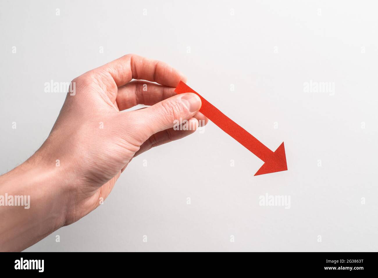 Hand holding a red paper arrow pointing down to the right Stock Photo ...