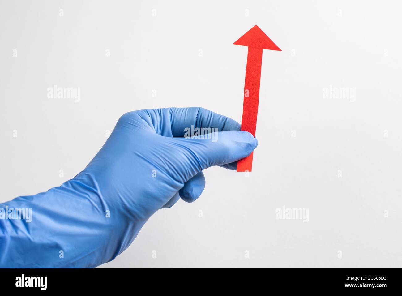 Hand in glove holding a red paper arrow pointing up on white background ...