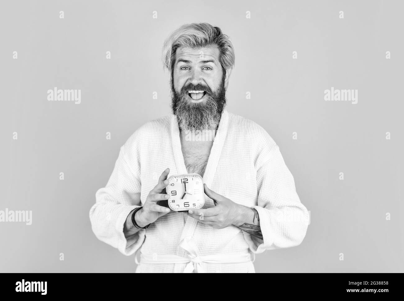 Time to wake up. Exhausted man being awakened by alarm clock in bedroom ...