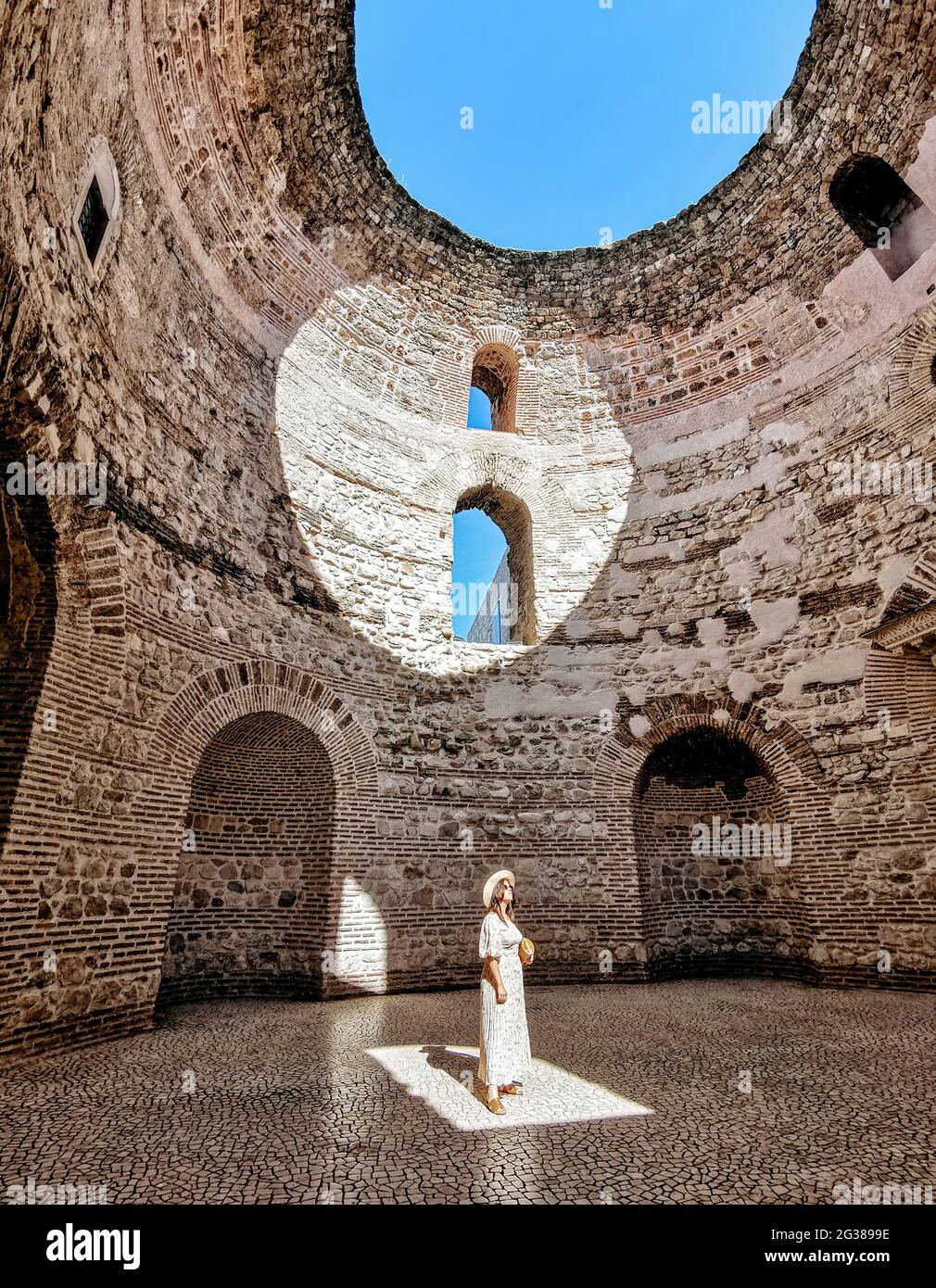 Woman standing inside ancient roman building with natural light shining ...