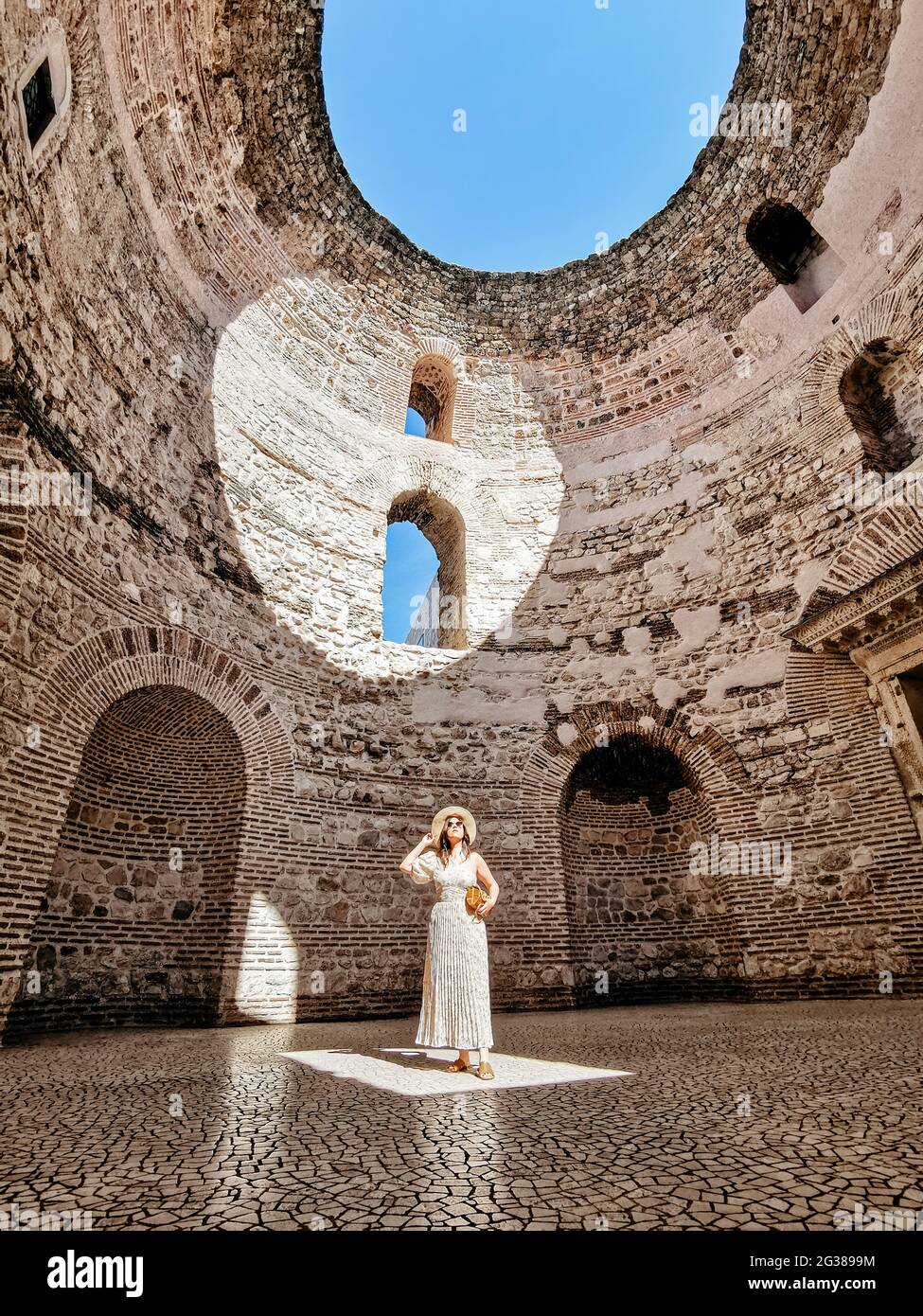 Woman standing inside ancient roman building with natural light shining ...