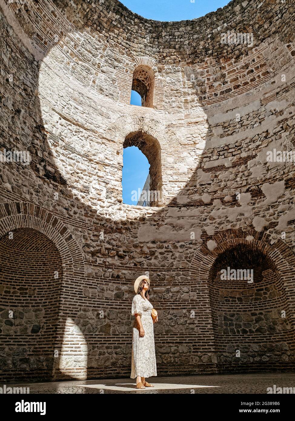 Woman standing inside ancient roman building with natural light shining ...