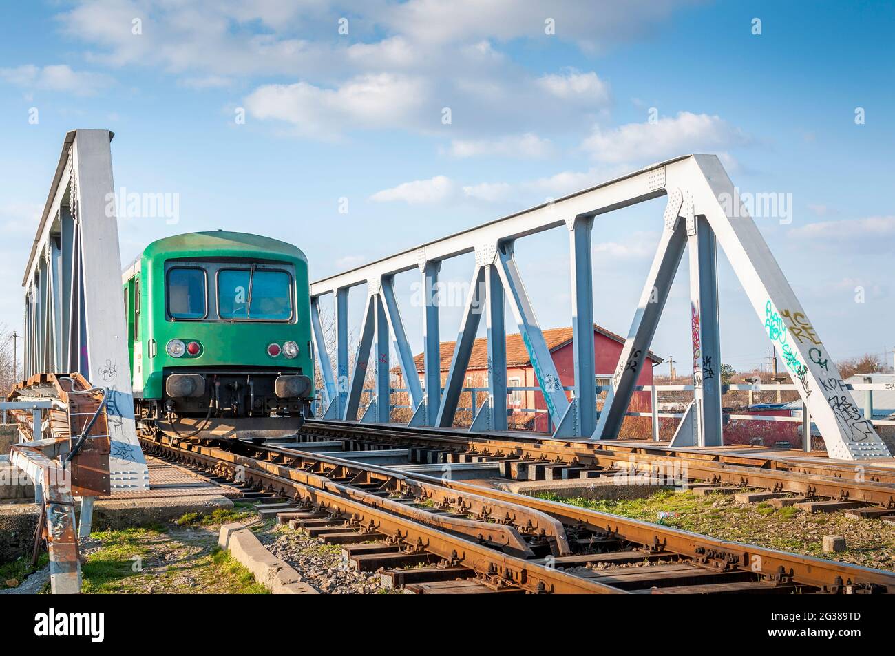 structure of gray metal railway bridge with a green train. Old railway ...