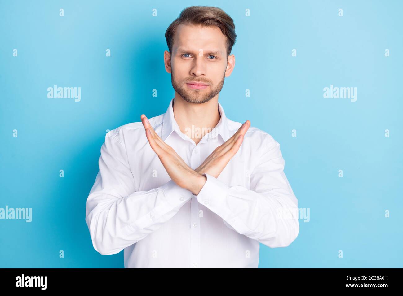 Portrait of attractive serious guy showing stop sign crossed hands ...