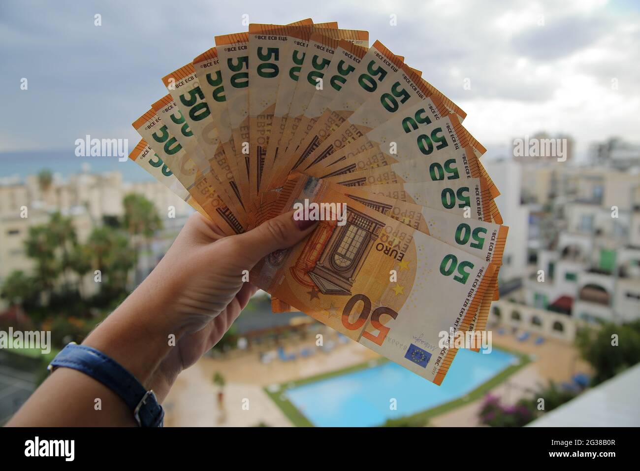 Range of new 50 euro banknotes in female hand close up against swimming ...
