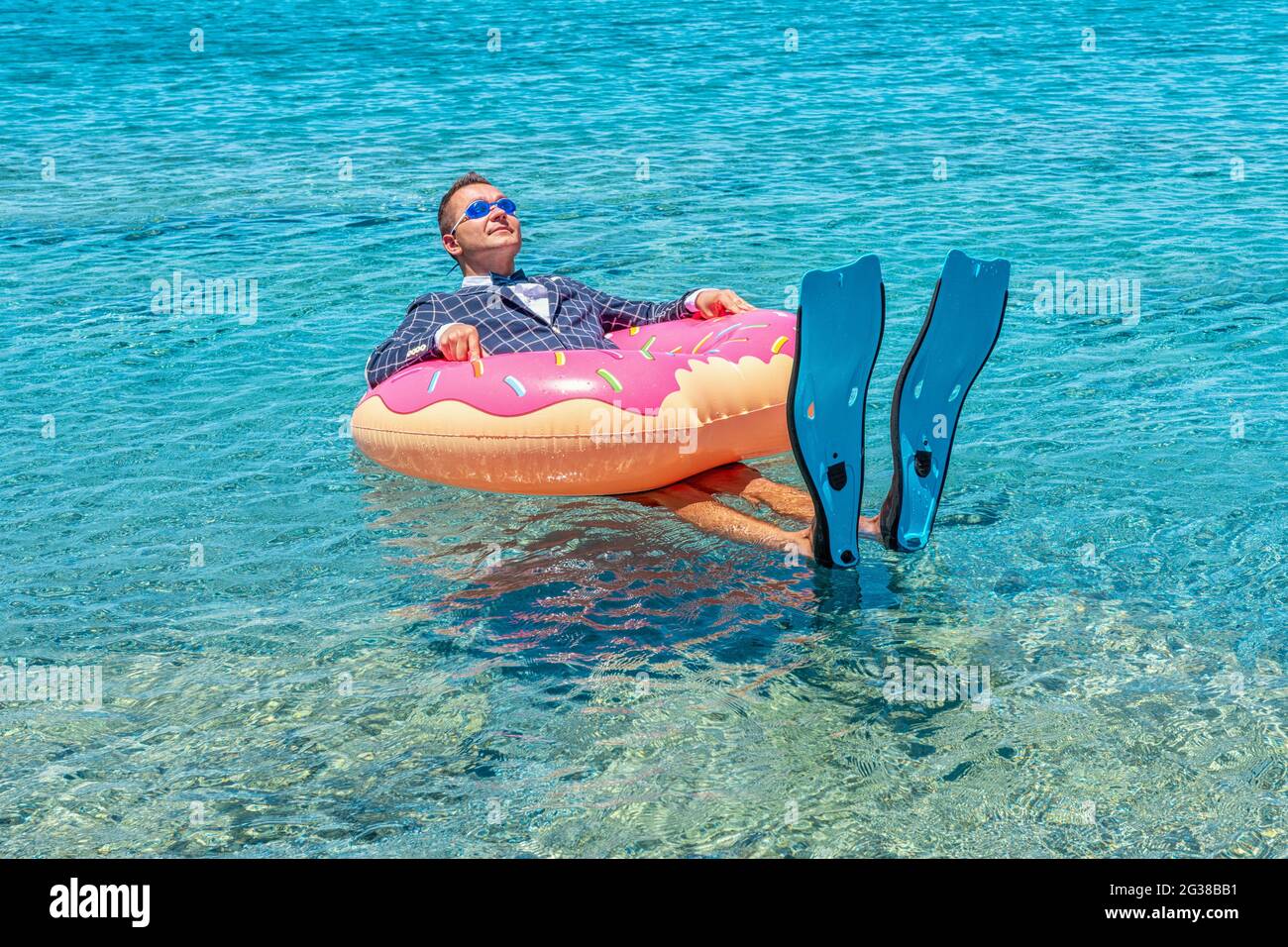 Happy businessman in flippers on an inflatable donut in the sea. Summer ...