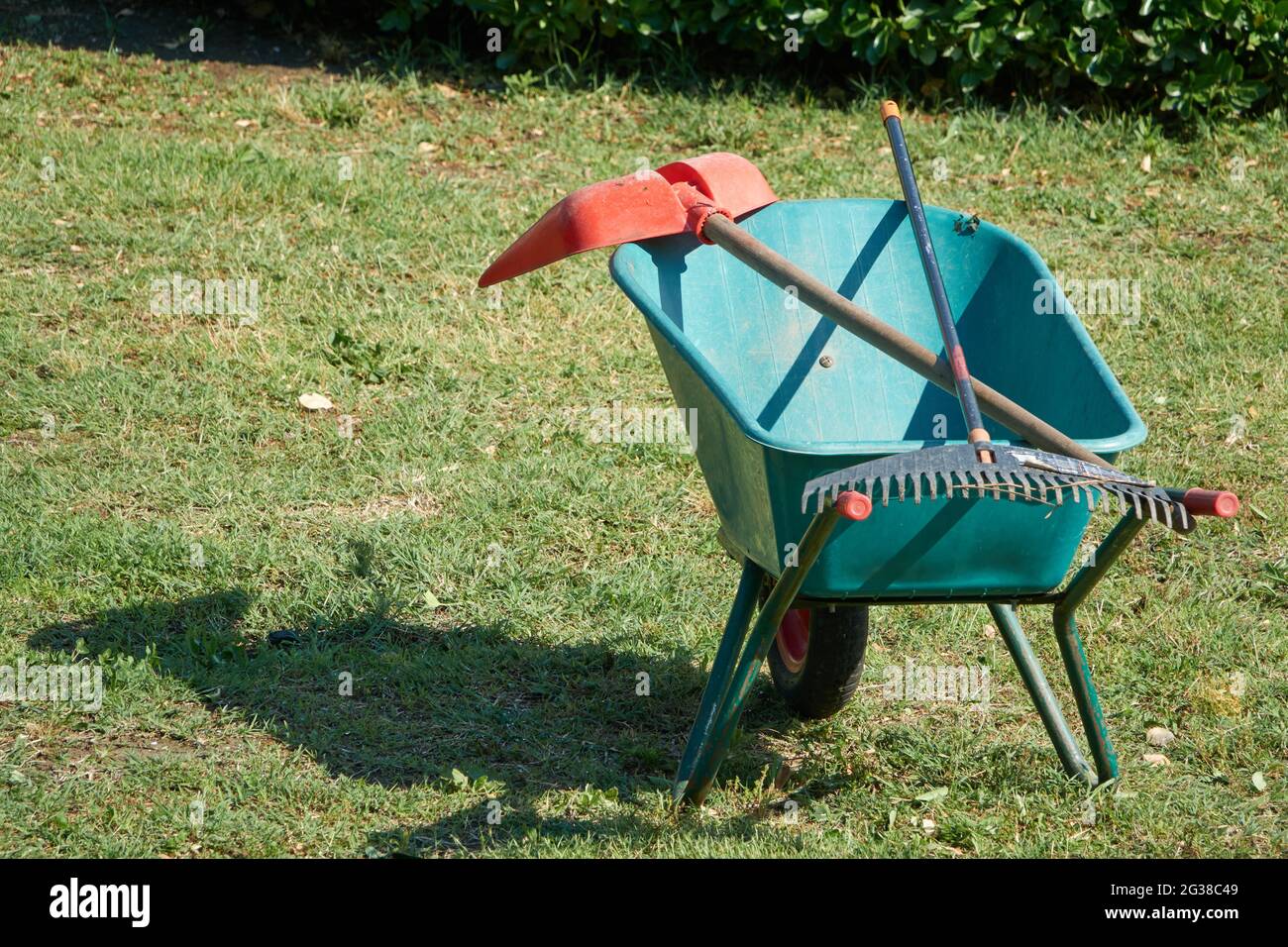 Gardening tools. Rake and garden shovel lying on wheelbarrow in the ...