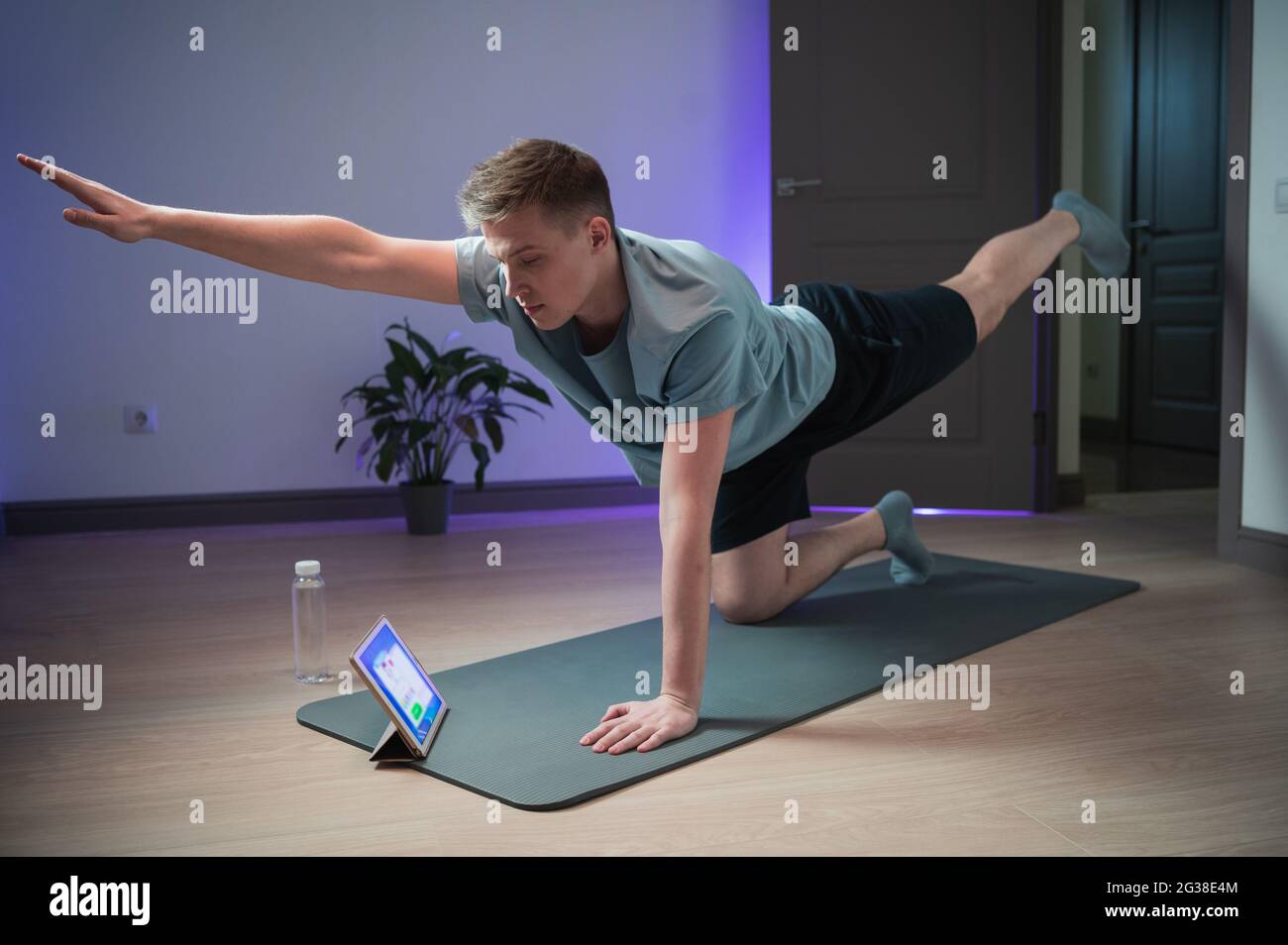 Stretching exercises at home, a young guy watches a video on a tablet ...
