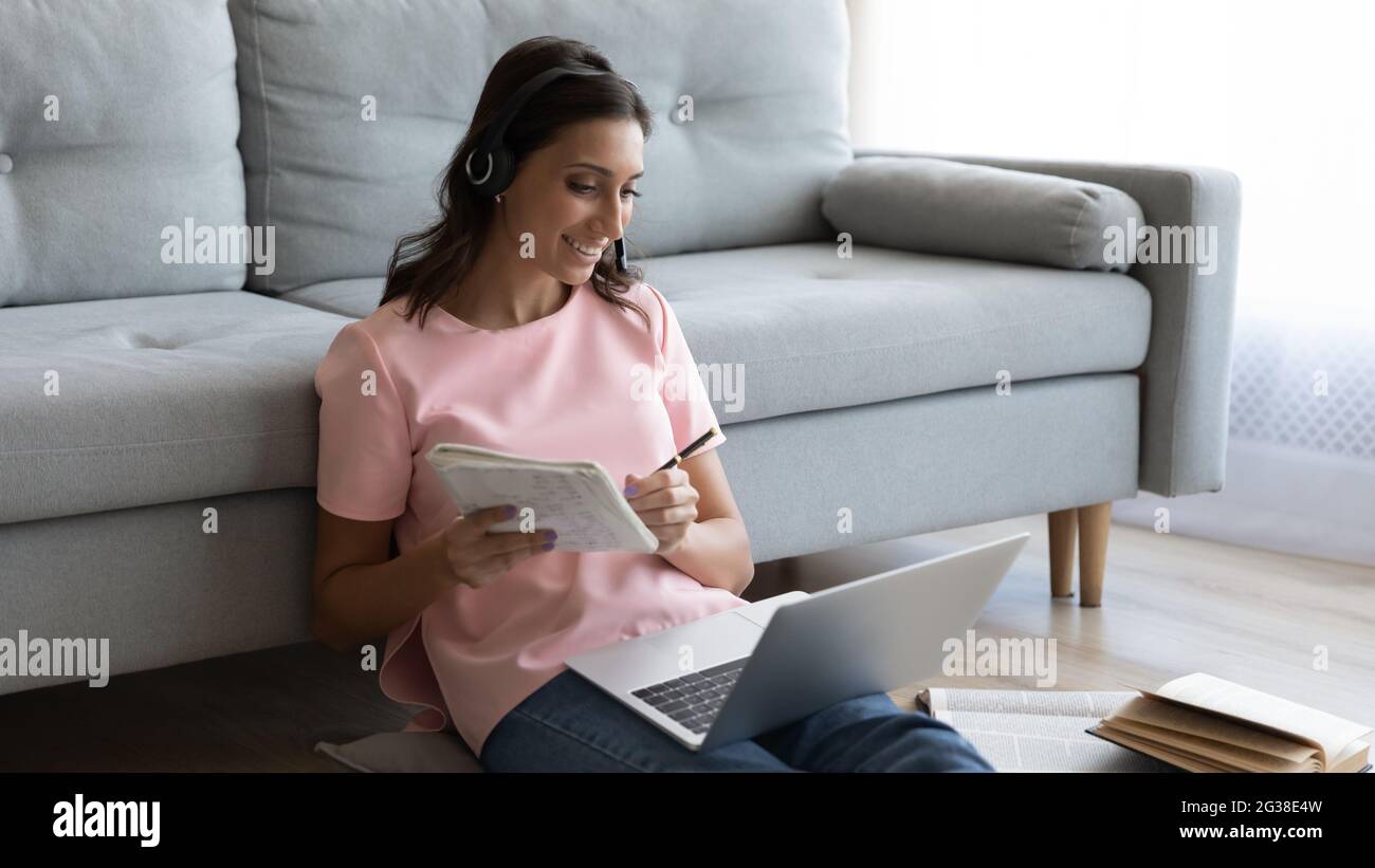Smiling Arabian woman in headphones taking notes, using laptop Stock ...