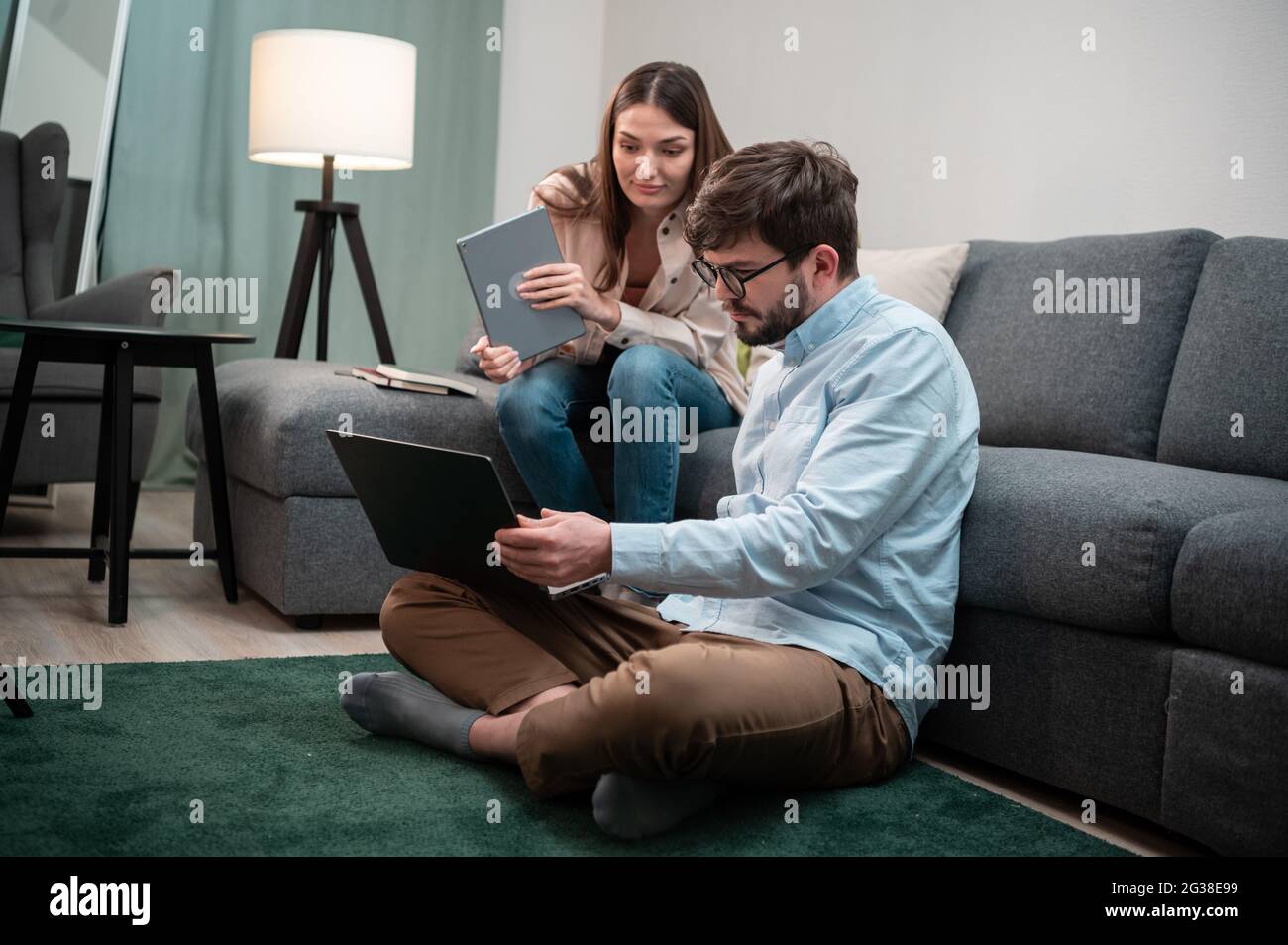 During remote work from home, the husband sits on the floor with a ...
