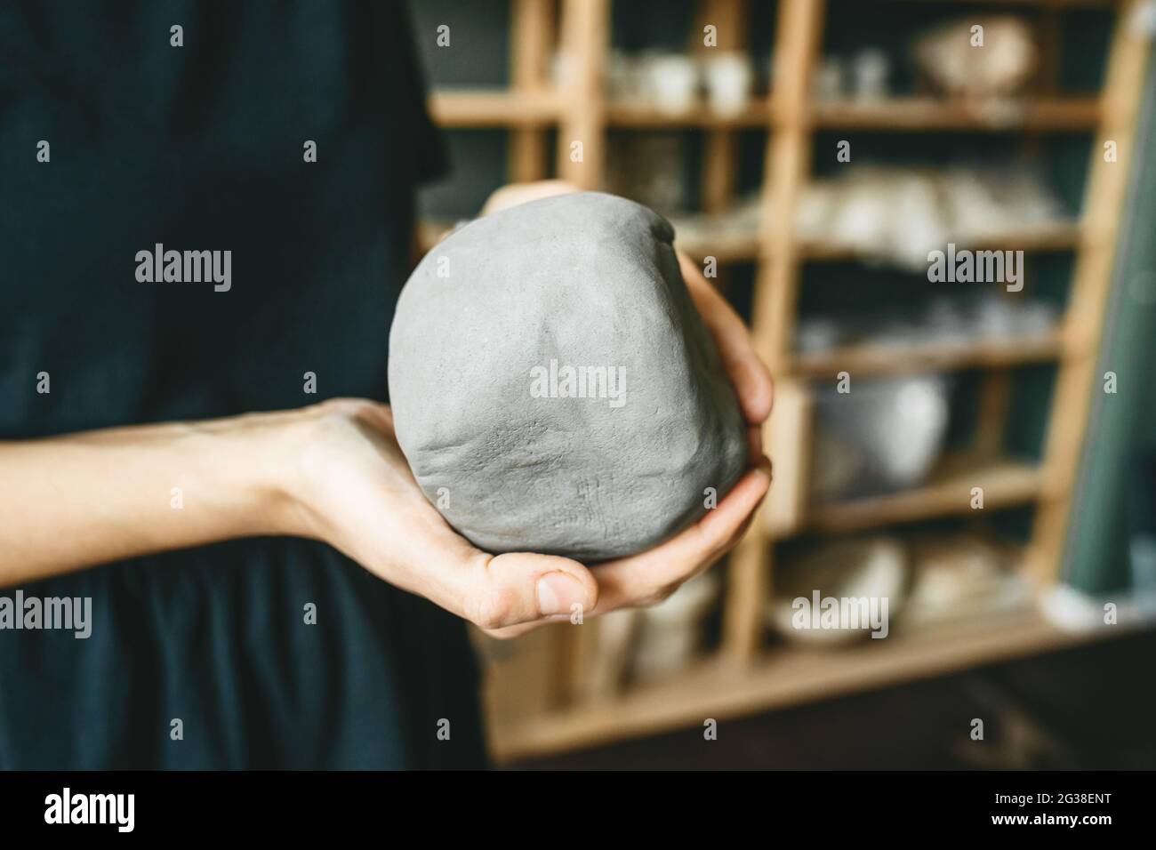Female hand holding piece of gray clay. Prepare to work in pottery ...