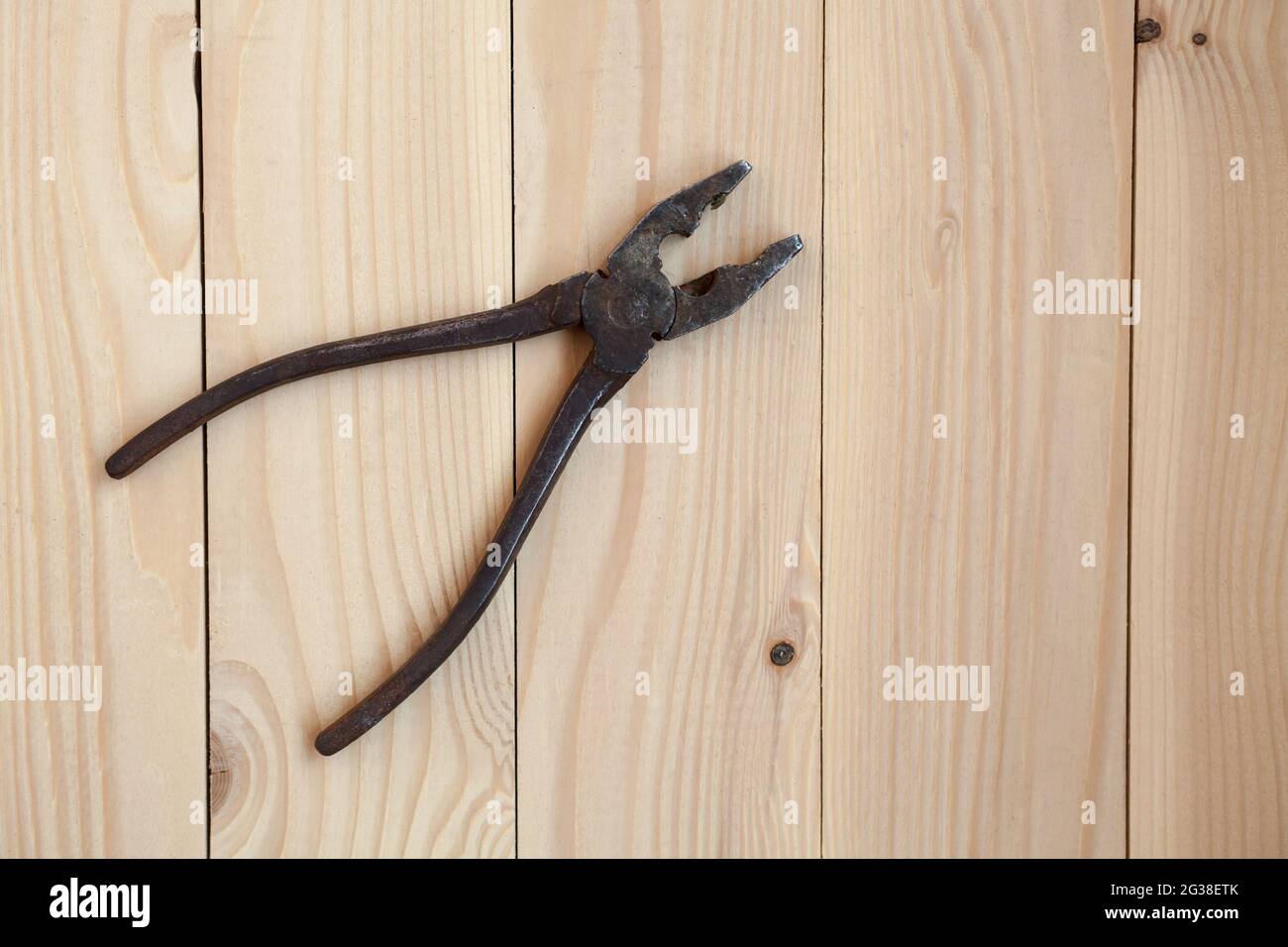 Old rusty pliers on a light wooden background. Pliers on the table ...