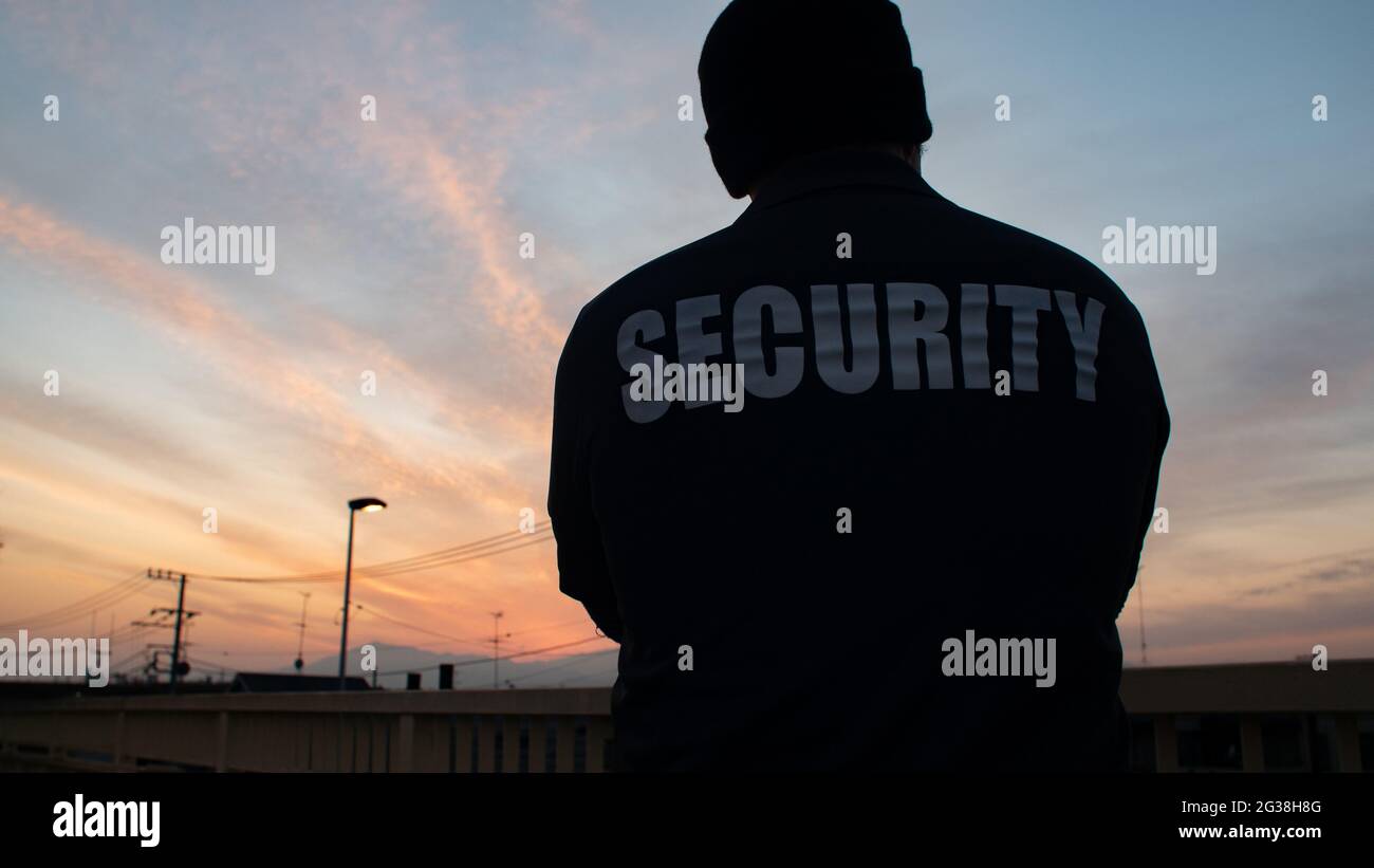 Rear view of a security guard looking down the street and sunset Stock ...