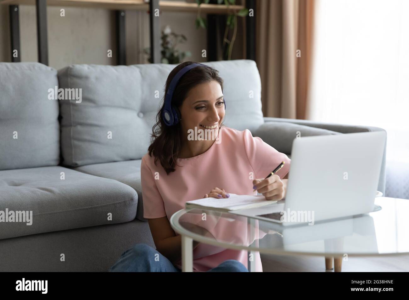Smiling Arabian woman in headphones using laptop, taking notes Stock ...