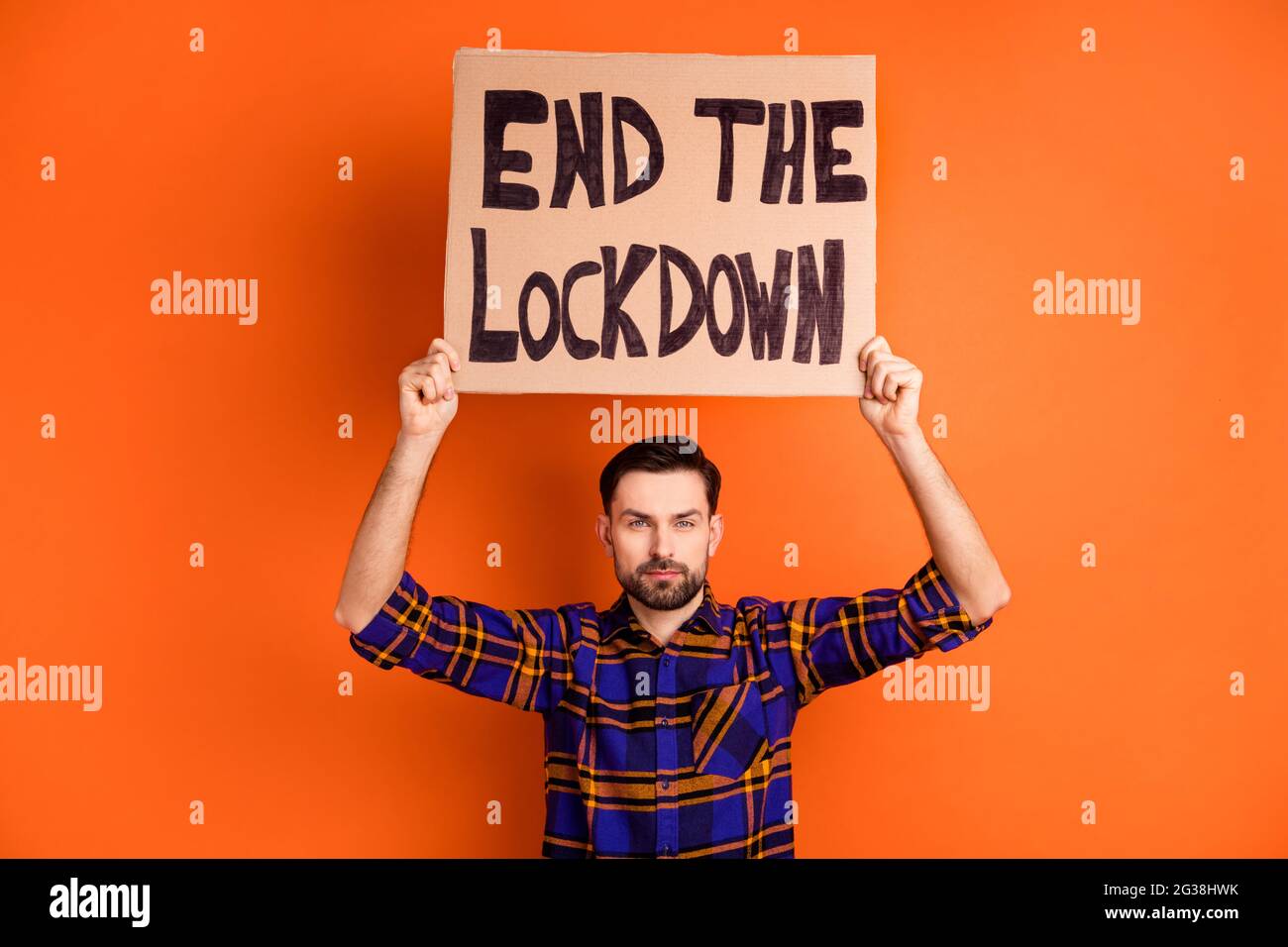 Portrait of handsome guy hands hold end the lockdown poster above head ...