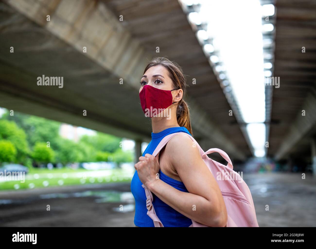 Fit girl waiting in parking lot under bridge carrying backpack. Young ...