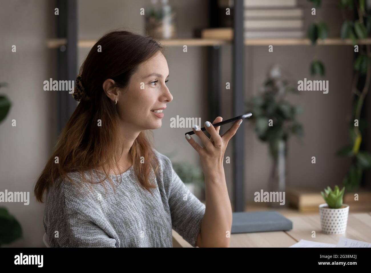 Side view smiling woman recording audio message on smartphone Stock ...