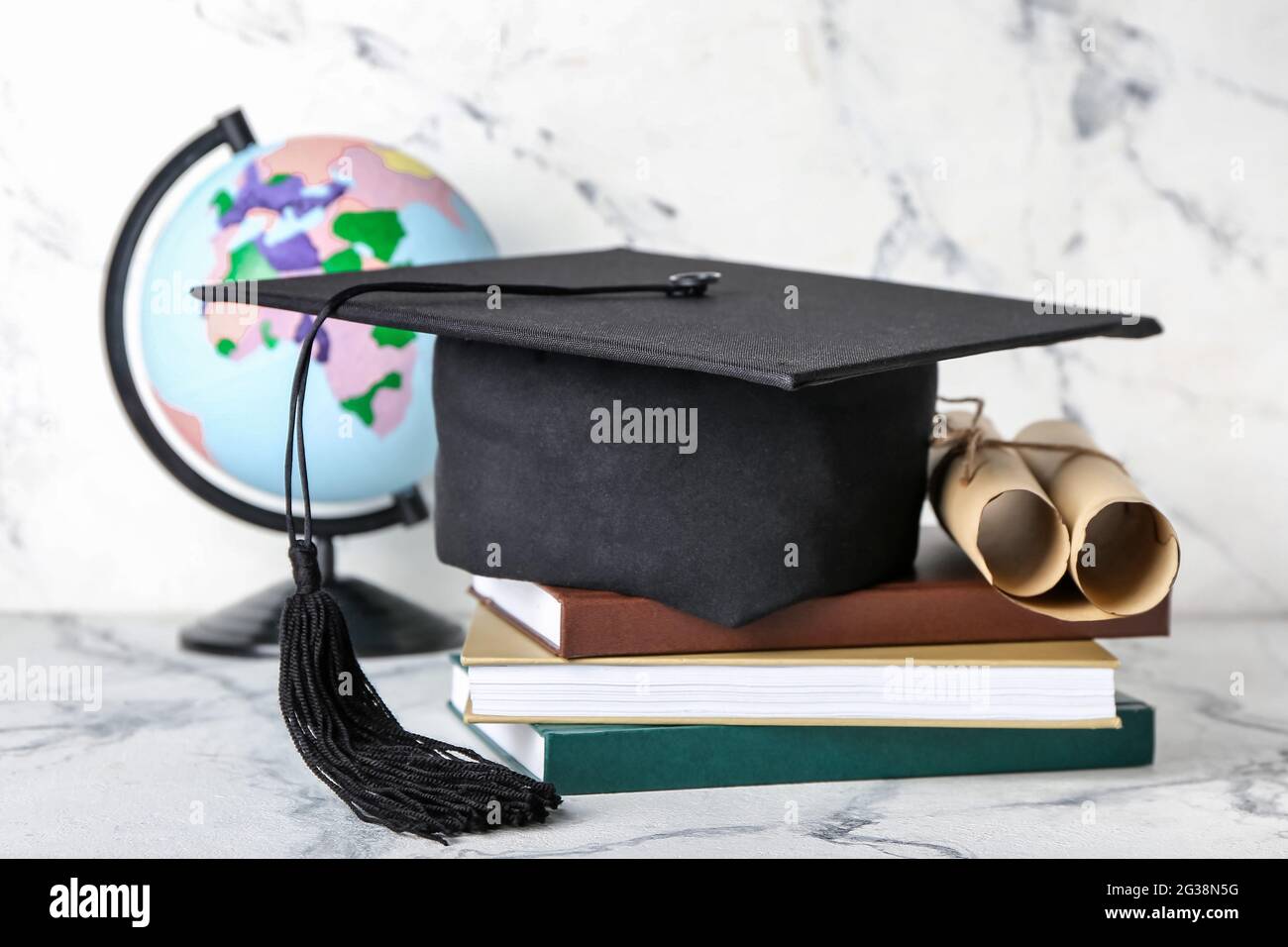 Graduation hat with books on light background Stock Photo - Alamy
