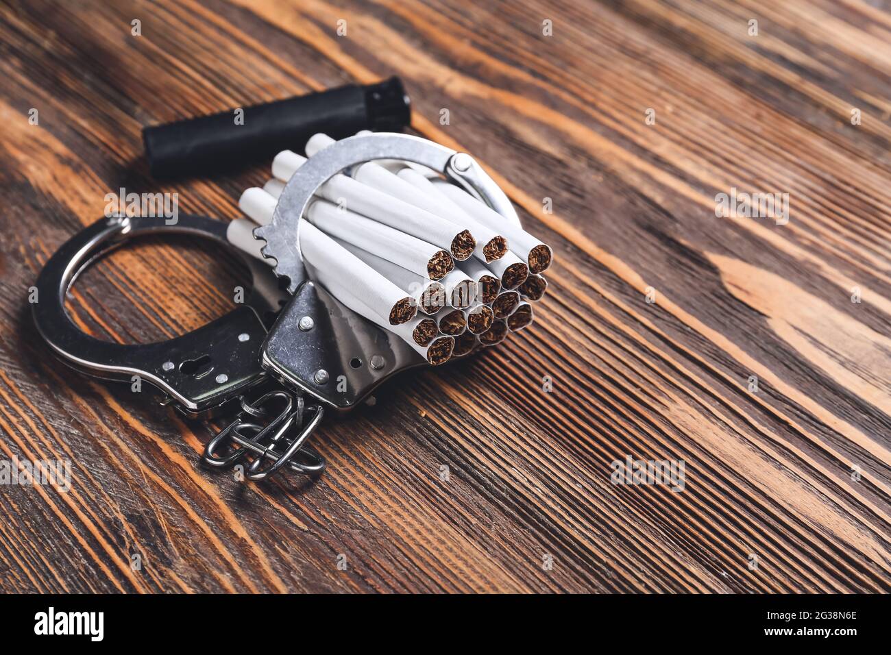 Cigarettes and handcuffs on wooden background. Concept of addiction ...