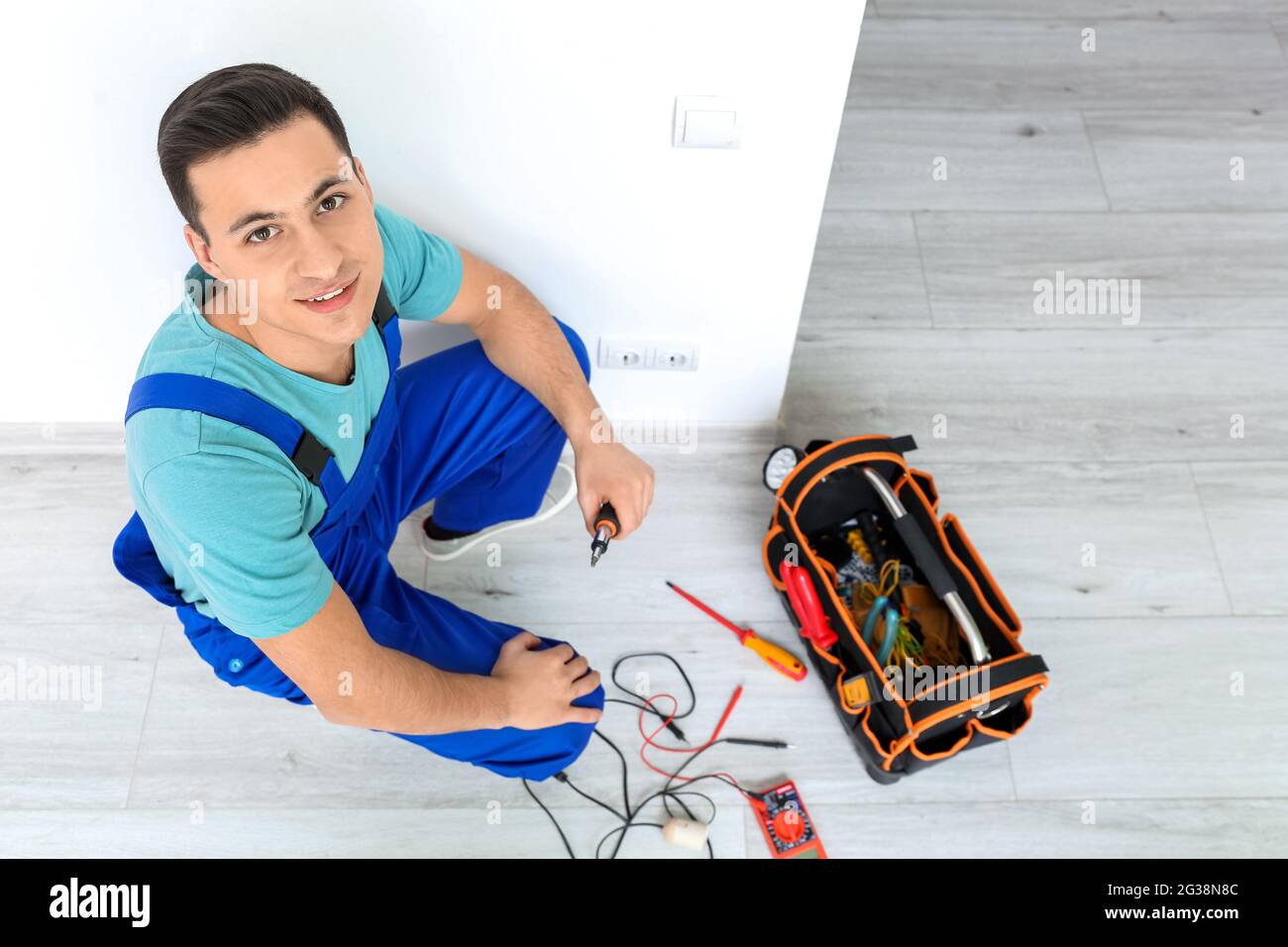 Young electrician repairing socket in room Stock Photo - Alamy