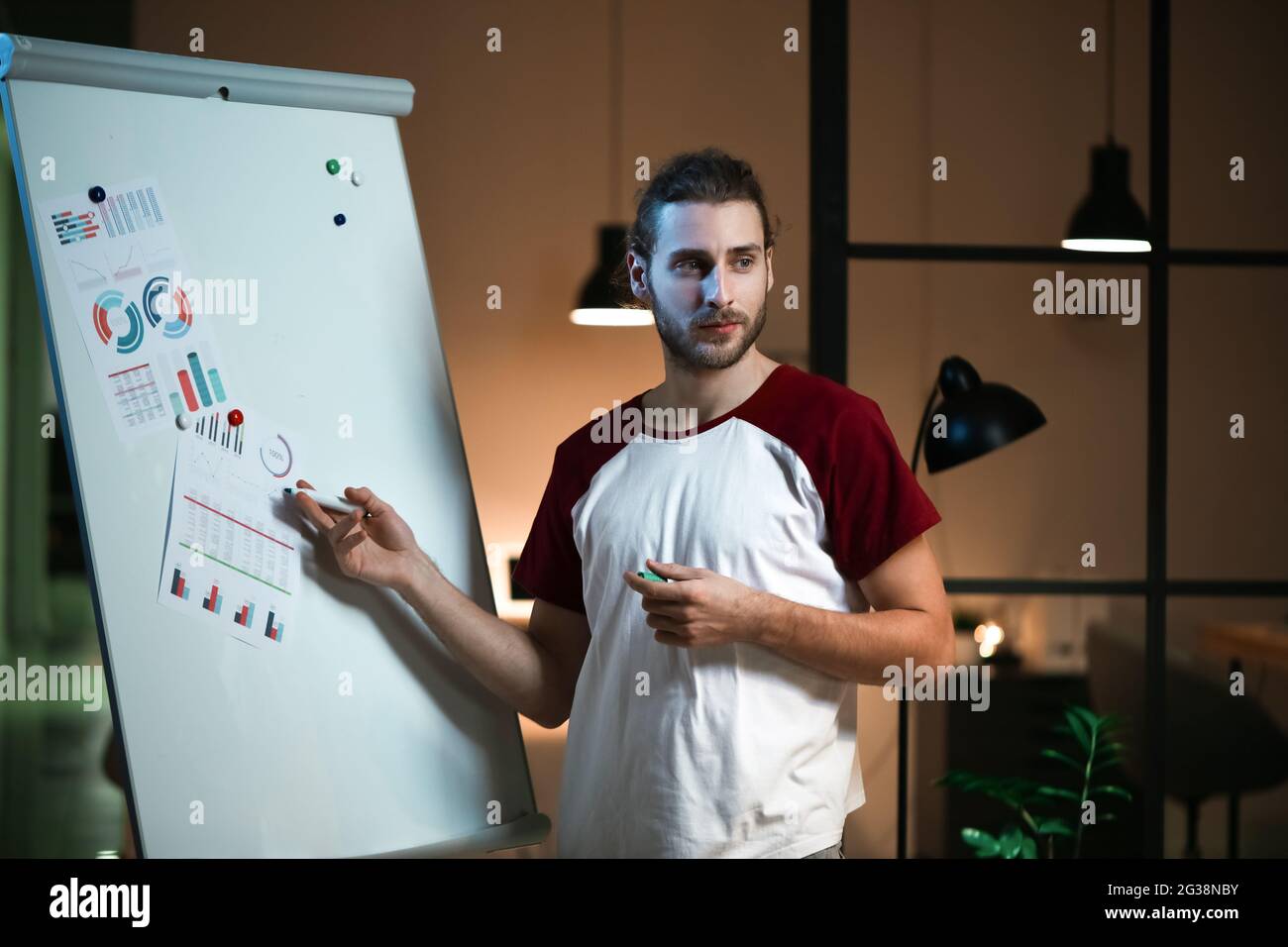 Young man giving presentation in office at night Stock Photo - Alamy