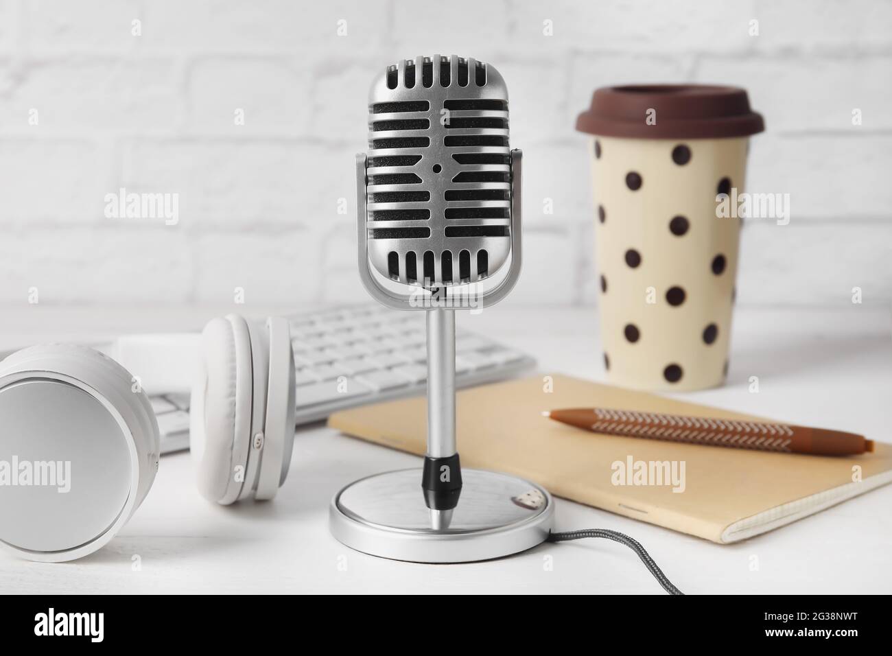 Modern microphone with headphones and takeaway cup on light background ...