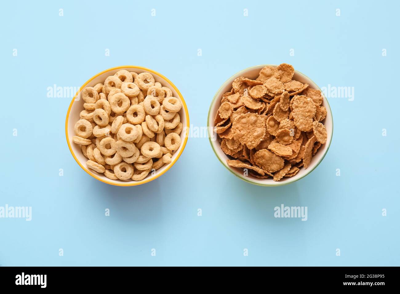 Bowls with tasty corn flakes and cereal rings on color background Stock ...