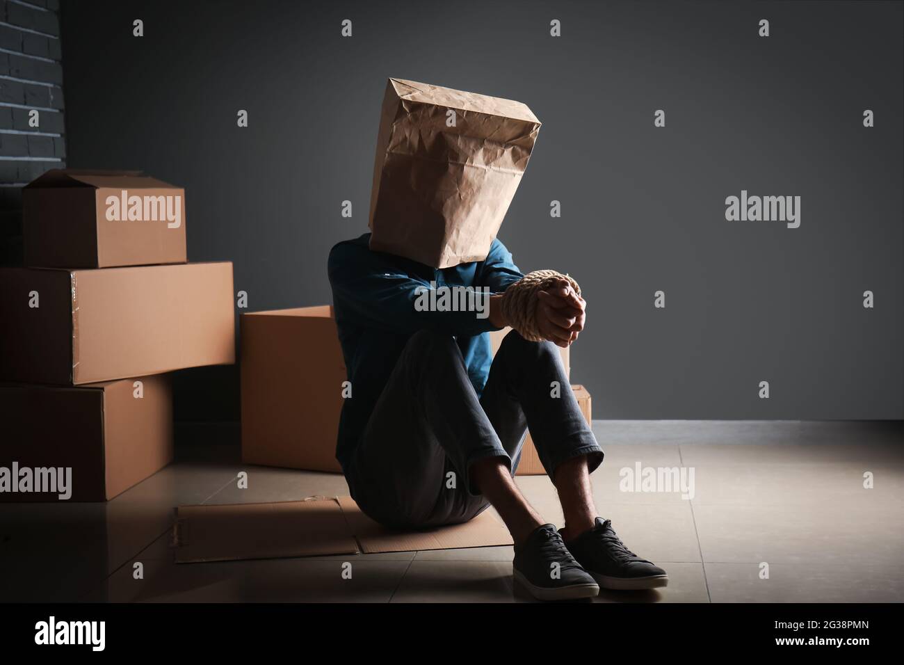 Male hostage with paper bag sitting on floor in room Stock Photo - Alamy
