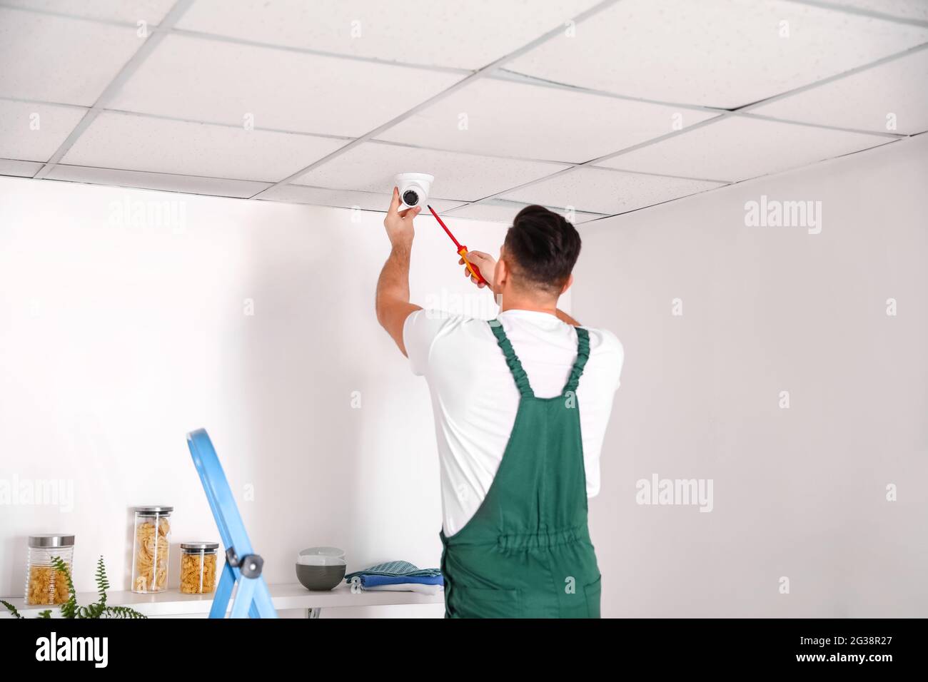 Worker installing CCTV camera in room Stock Photo - Alamy