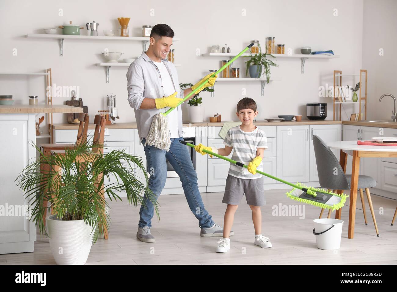 Father and son having fun while mopping floor in kitchen Stock Photo ...