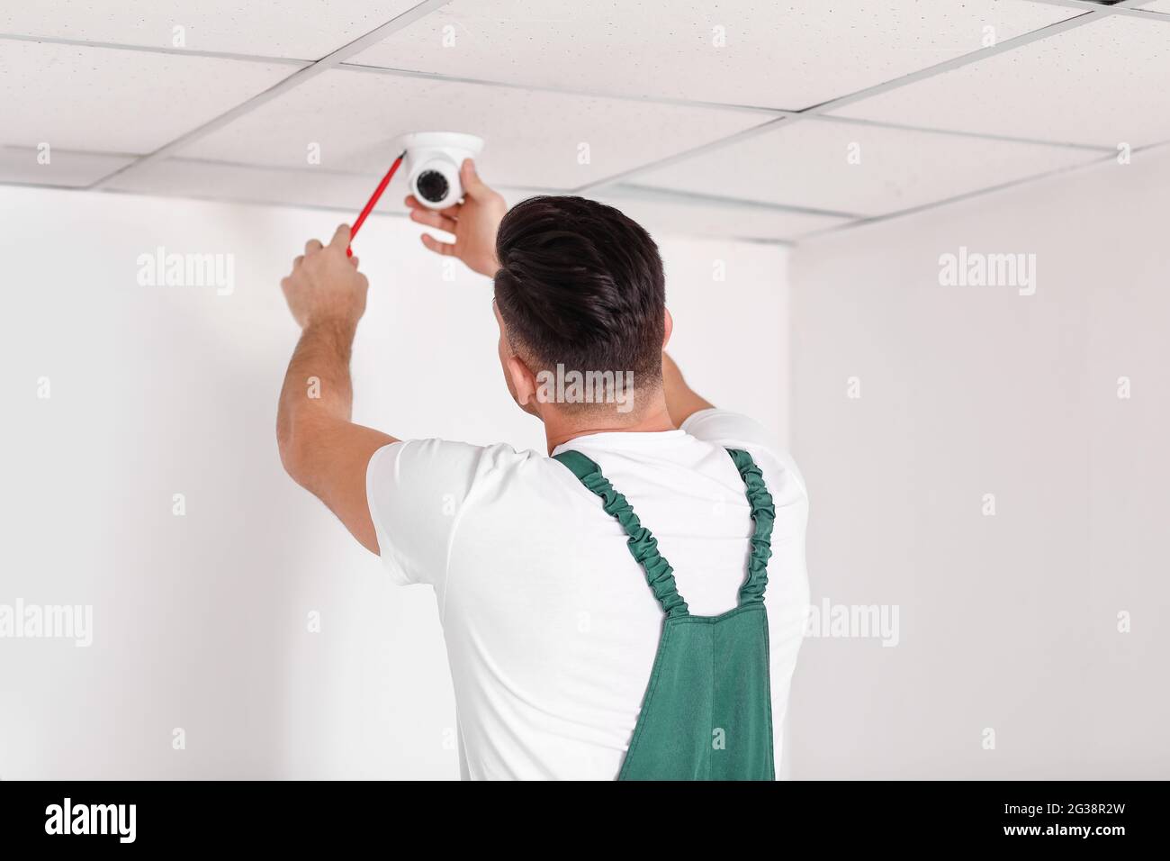 Worker installing CCTV camera in room Stock Photo - Alamy