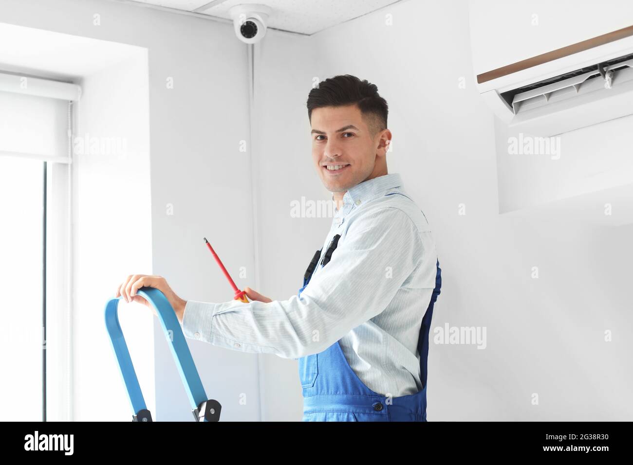 Worker installing CCTV camera in room Stock Photo - Alamy