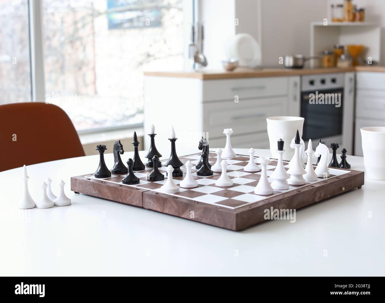 Board with chess pieces on dining table in kitchen Stock Photo - Alamy
