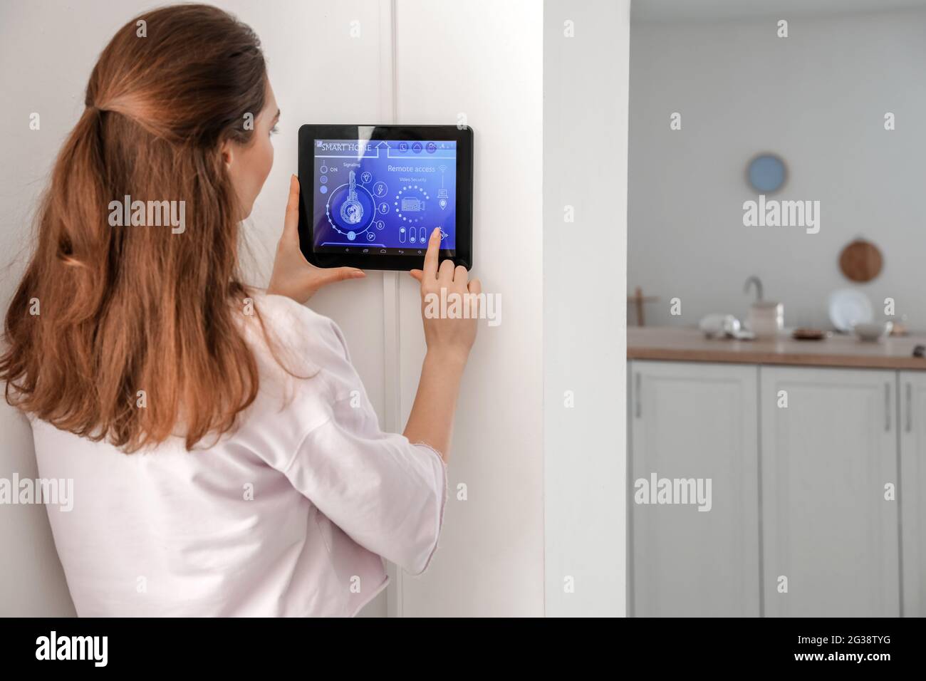 Woman using smart home security system control panel Stock Photo - Alamy