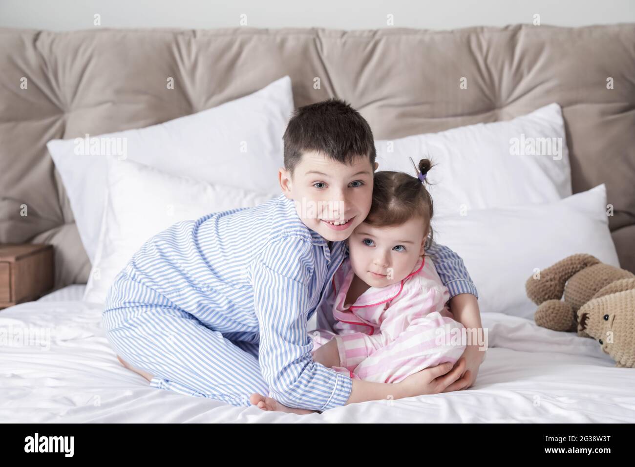 Cute little children sitting on bed Stock Photo - Alamy
