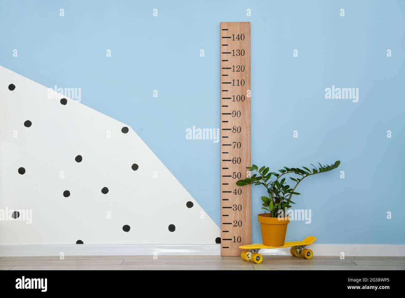 Wooden stadiometer and houseplant near color wall Stock Photo - Alamy