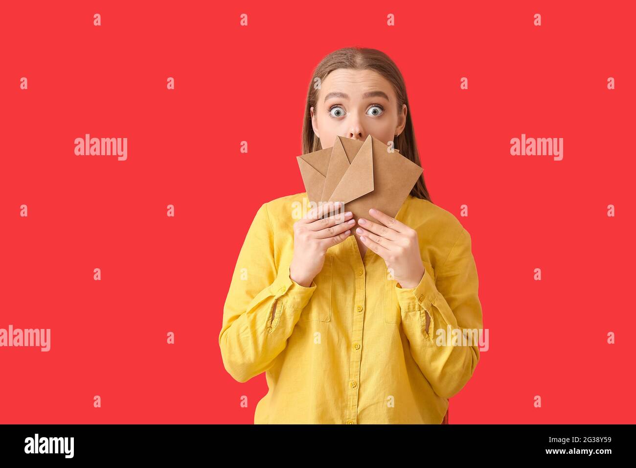 Shocked young woman with letters on color background Stock Photo - Alamy